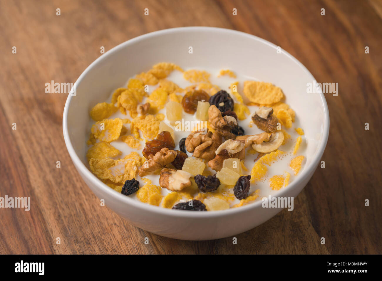 corn flakes with nuts and fruits in white bowl on wood table Stock ...