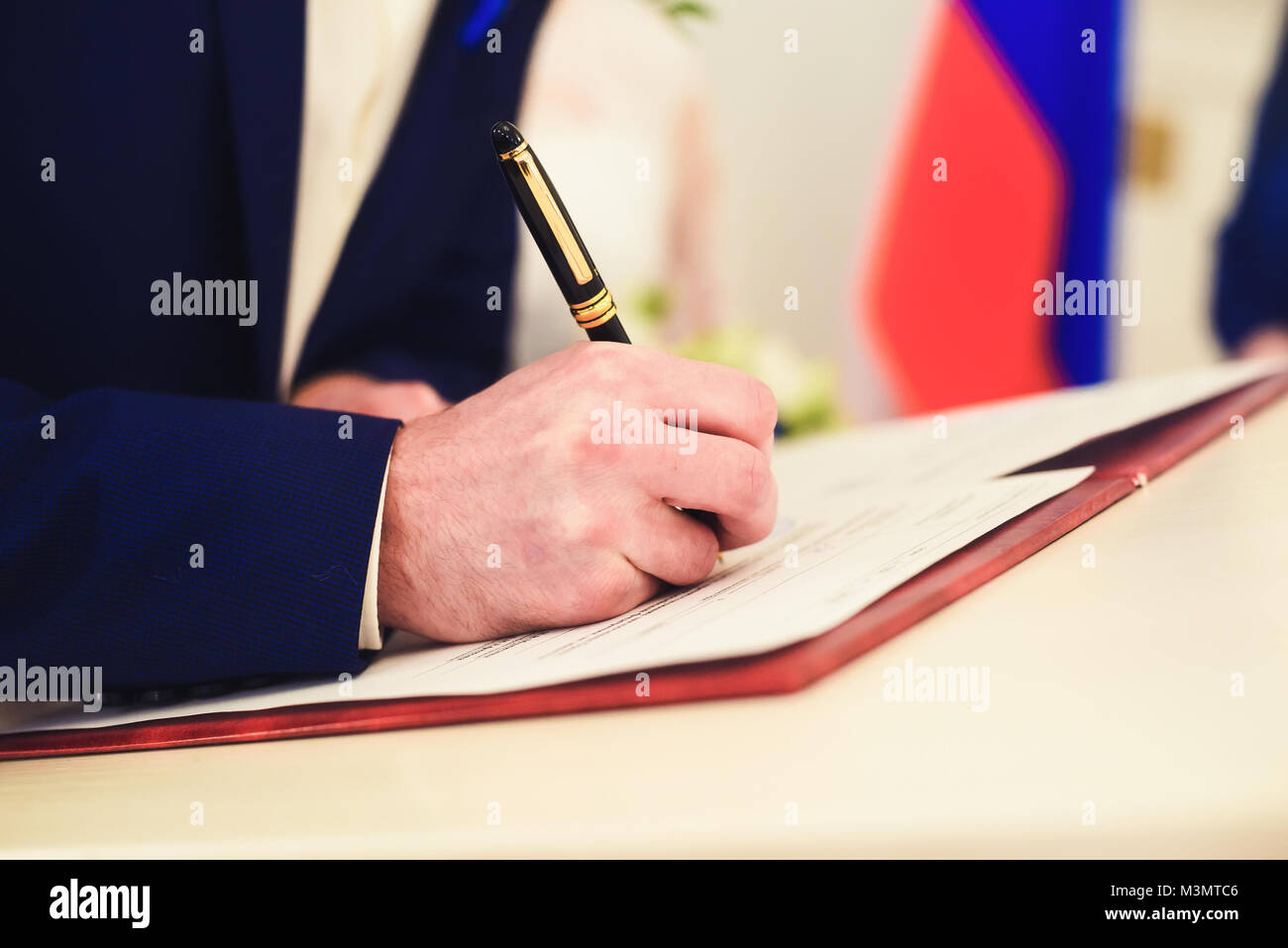 The pen in the right hand signs papers with a shallow depth of field ...