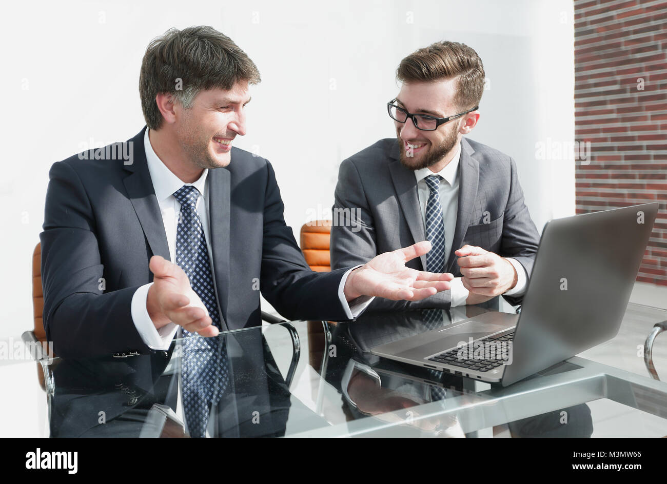 Portrait of two business people sitting at office desk Stock Photo - Alamy