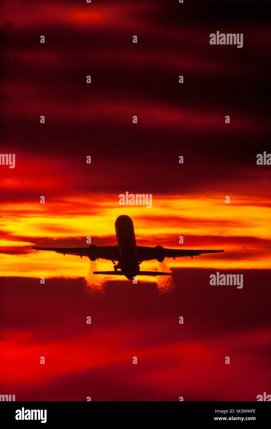 A jet commercial airliner takes off and climbs into a colorful dawn sky ...
