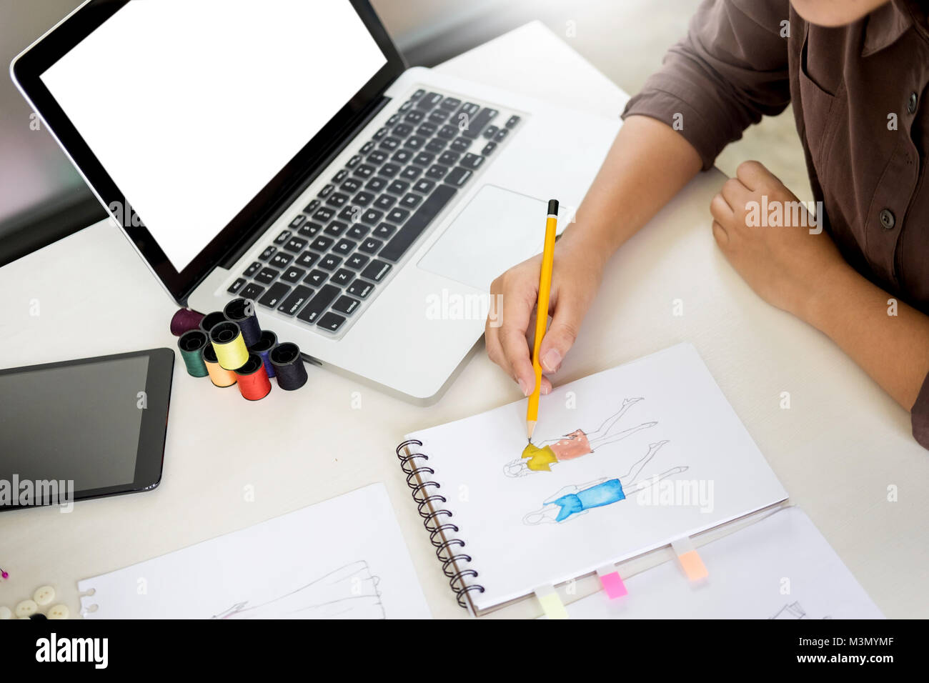 two young men working as fashion designers and drawing sketches and ...