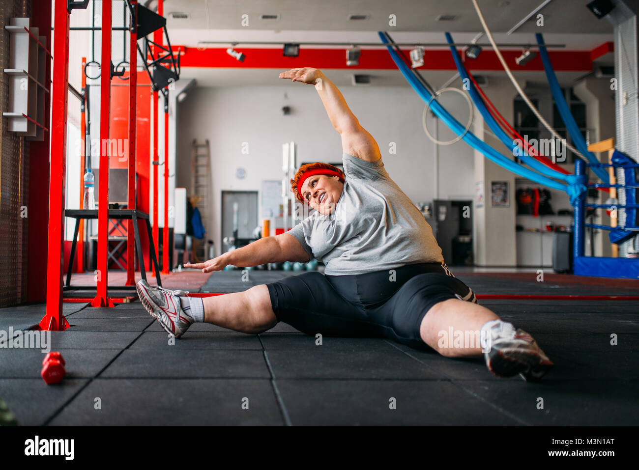 Fat woman exercises on the floor, workout in gym. Calories burning ...