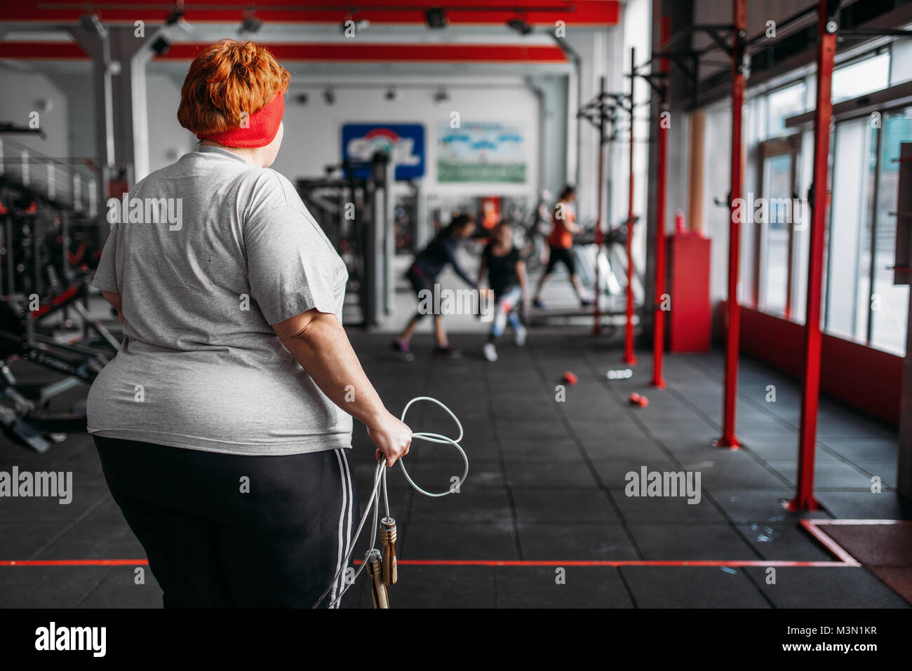 Fat sweaty woman, fit training with rope in gym. Calories burning ...
