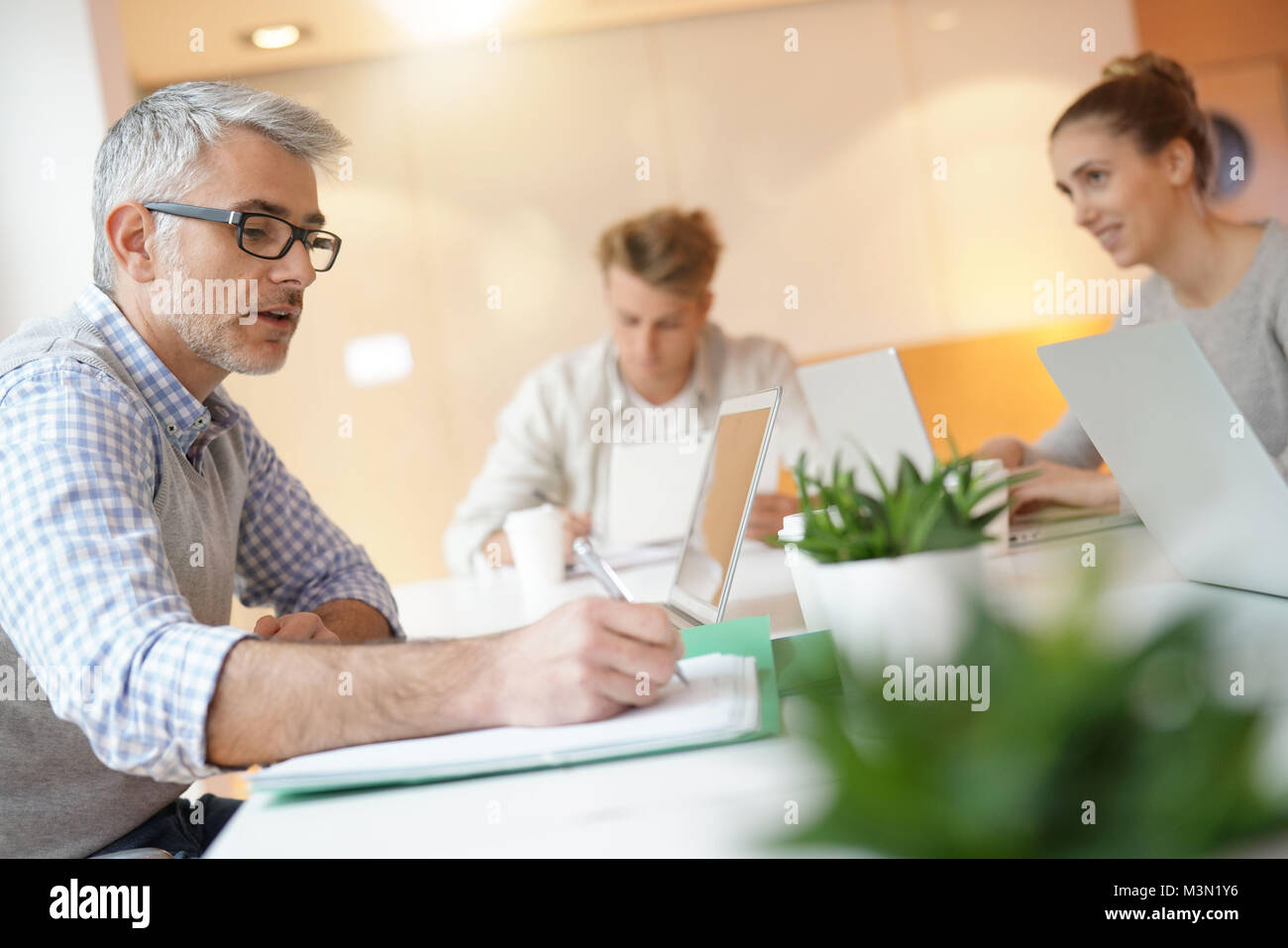 Teacher meeting around table with students Stock Photo - Alamy