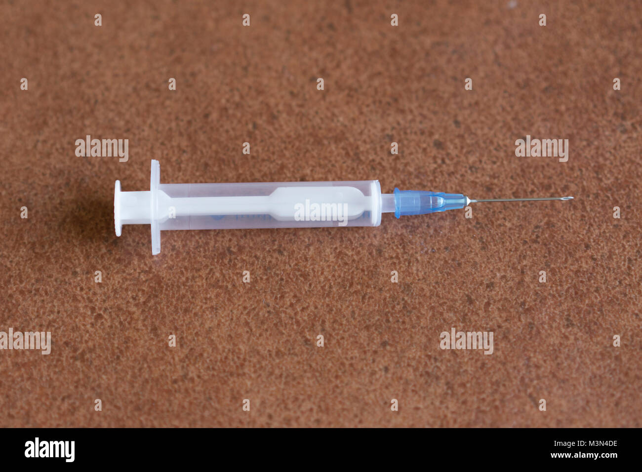 Syringe for injection on a brown background Stock Photo - Alamy