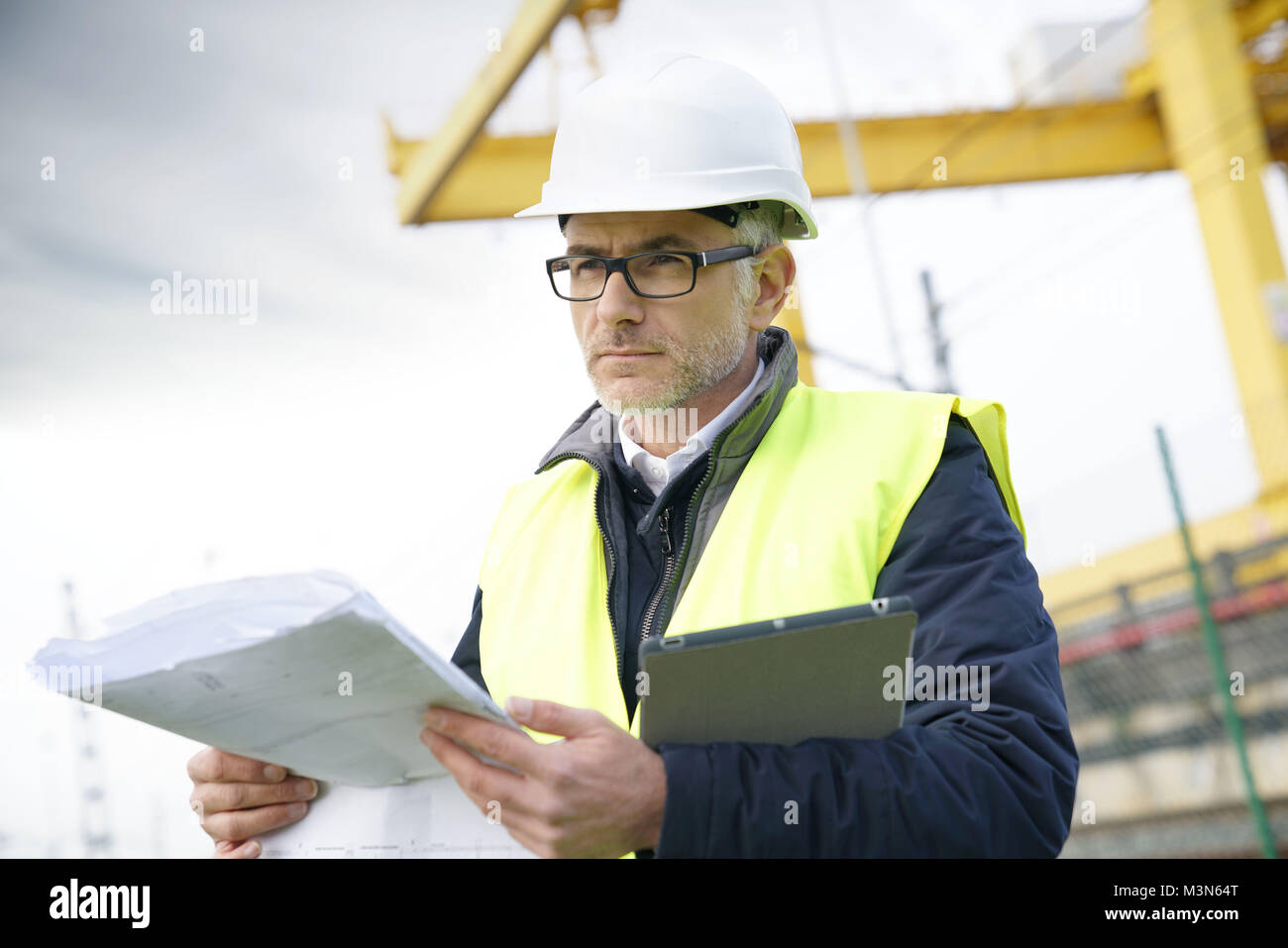 Construction manager on site reading blueprint Stock Photo - Alamy