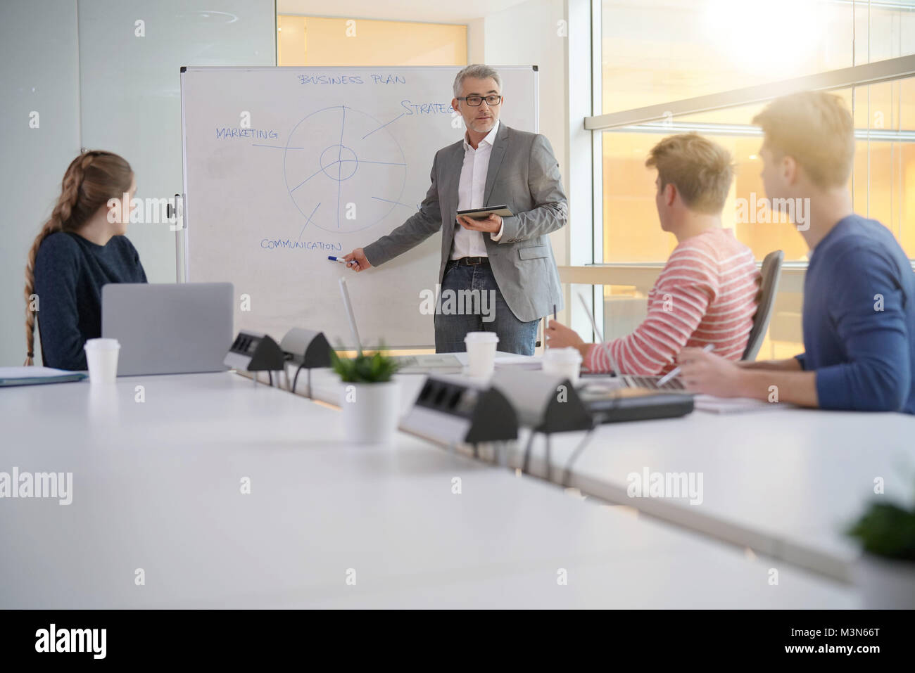Economics teacher giving business class to students Stock Photo - Alamy