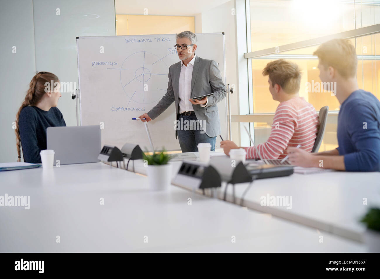 Economics teacher giving business class to students Stock Photo - Alamy