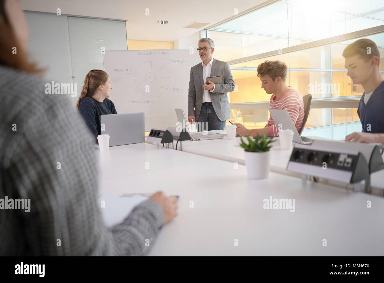 Economics teacher giving business class to students Stock Photo - Alamy