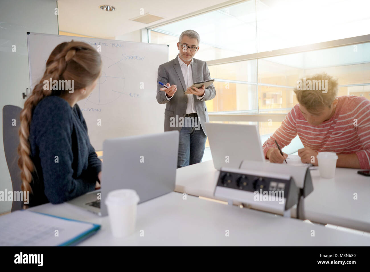 Economics teacher giving business class to students Stock Photo - Alamy