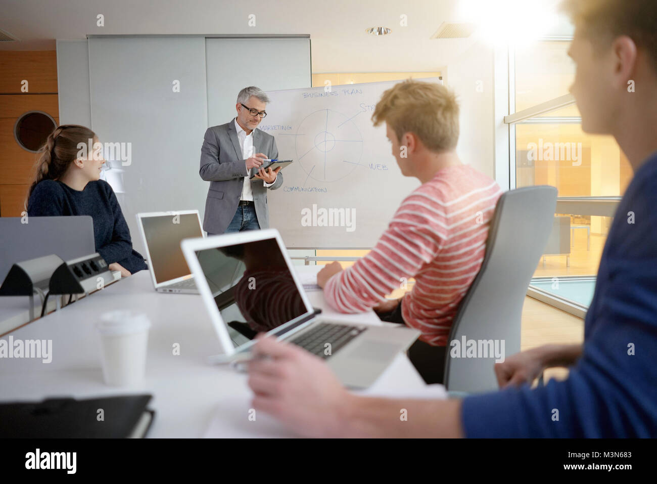 Economics teacher giving business class to students Stock Photo - Alamy