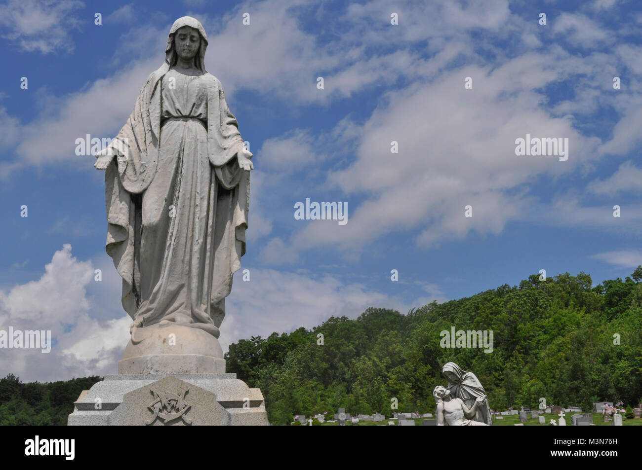 Statue Looking Down Upon a Grave with a Cloudy Blue Sky Background ...