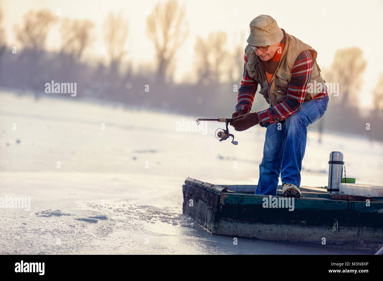 Winter season – smiling fisherman fishing on the frozen lake Stock ...