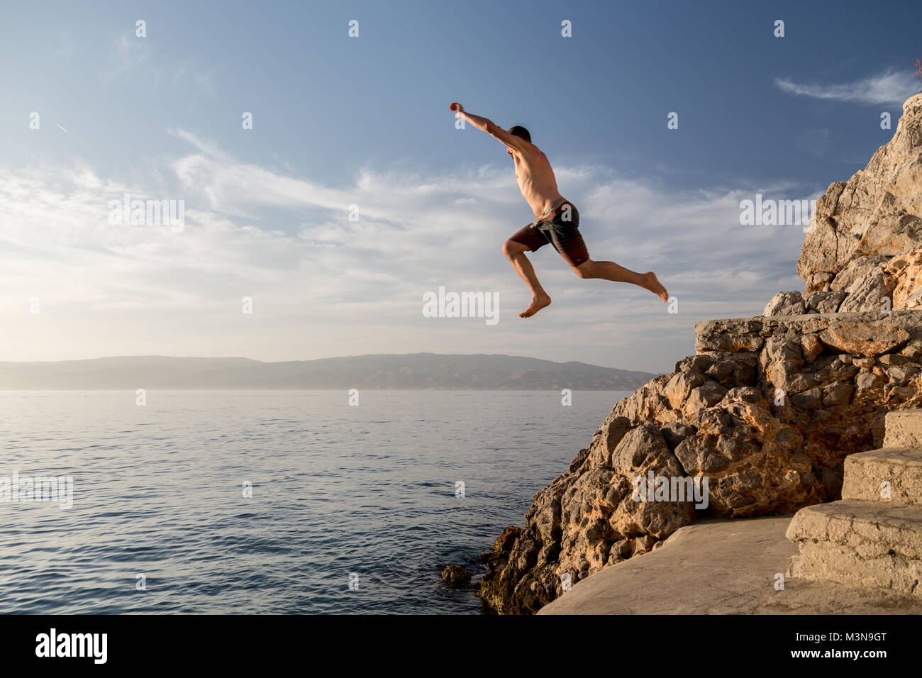 Man jumping from rocks Stock Photo - Alamy
