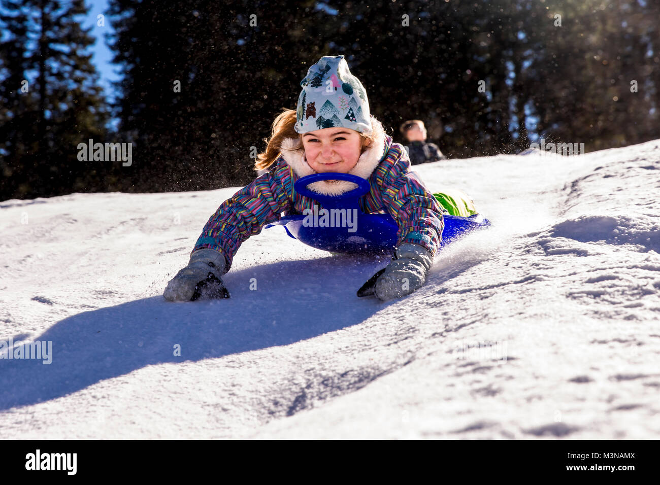 girl sledding down snowy hill on sled fast speed Stock Photo - Alamy
