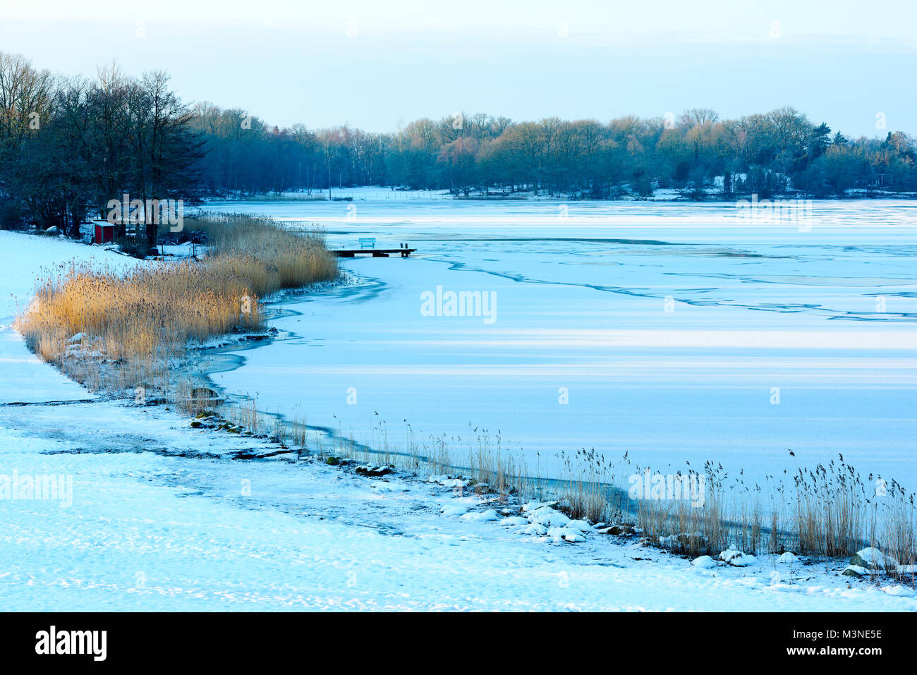 Cold morning landscape with frozen sea and thin snow cover on the shore ...
