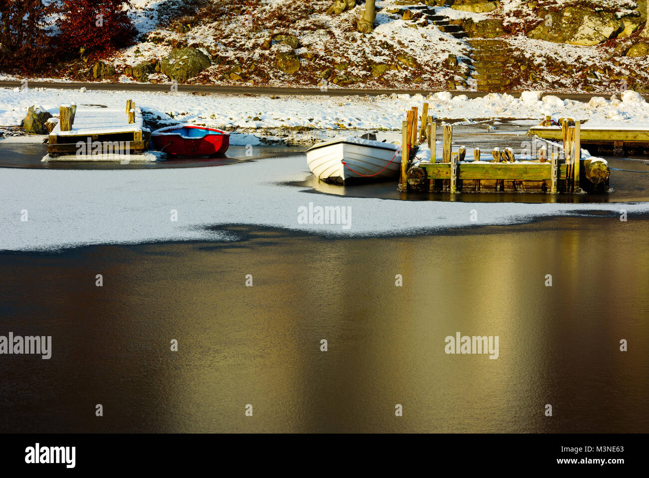 Two small boats moored at piers and frozen stuck by the cold winter ...