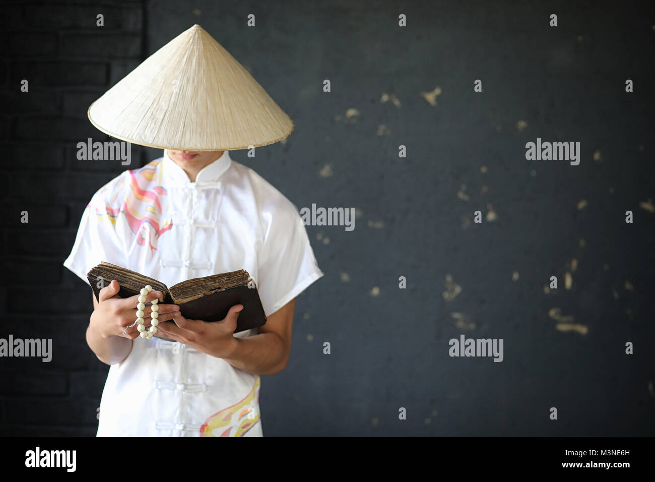 Asian young monk in hat on black wall Stock Photo - Alamy
