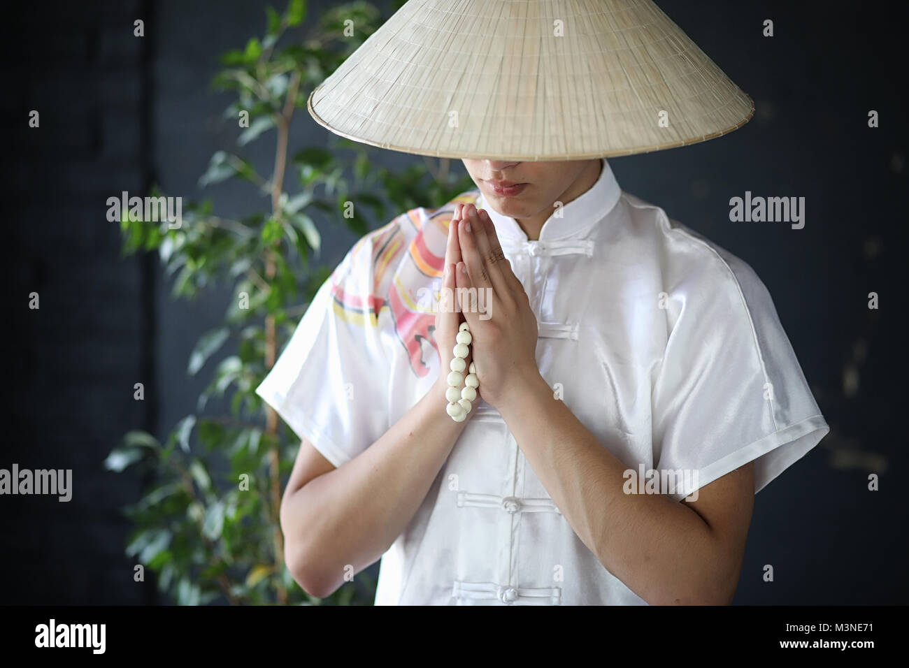 Asian young monk in hat on black wall Stock Photo - Alamy