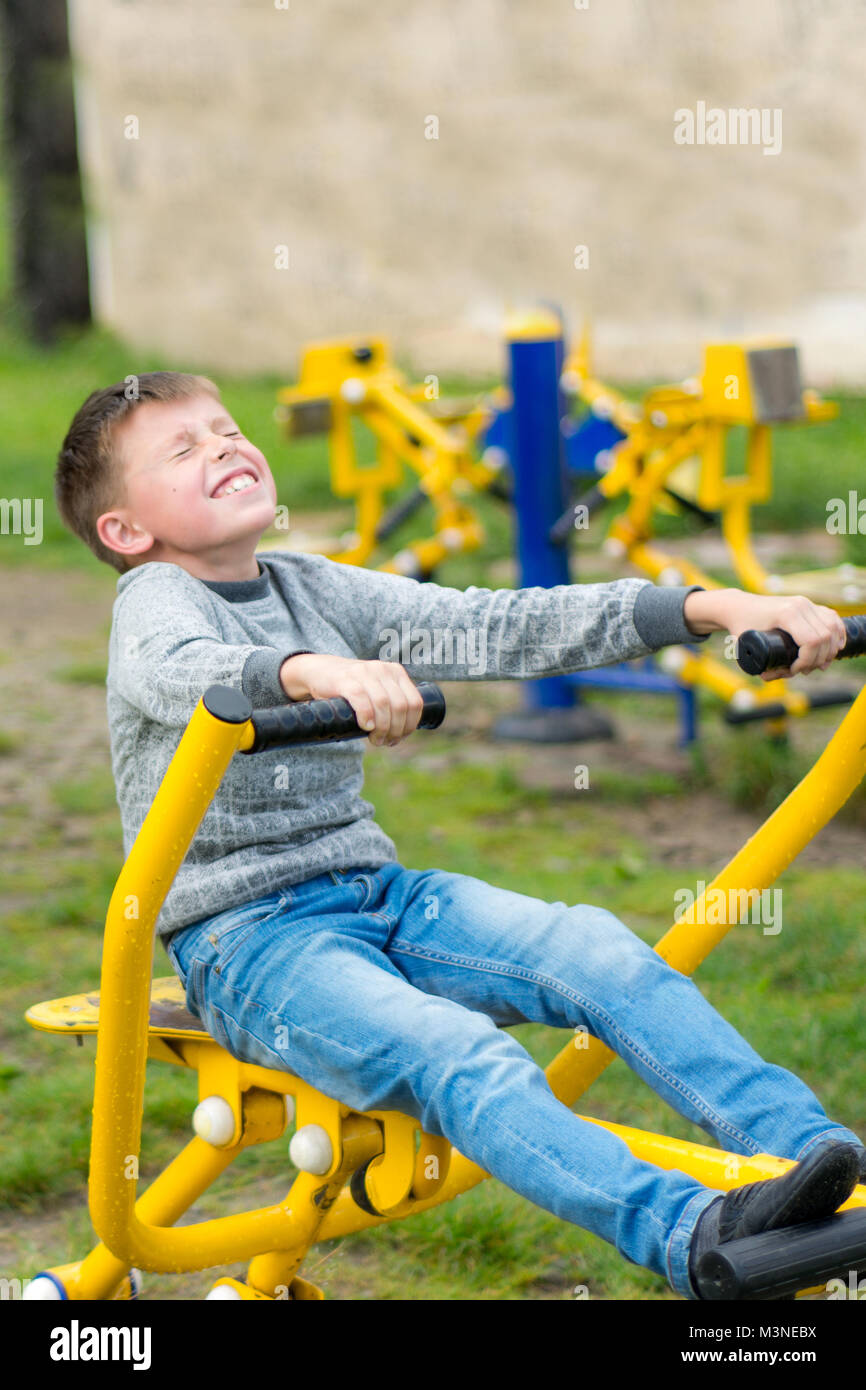 A beautiful little boy running on a track in a park on a sports ground ...