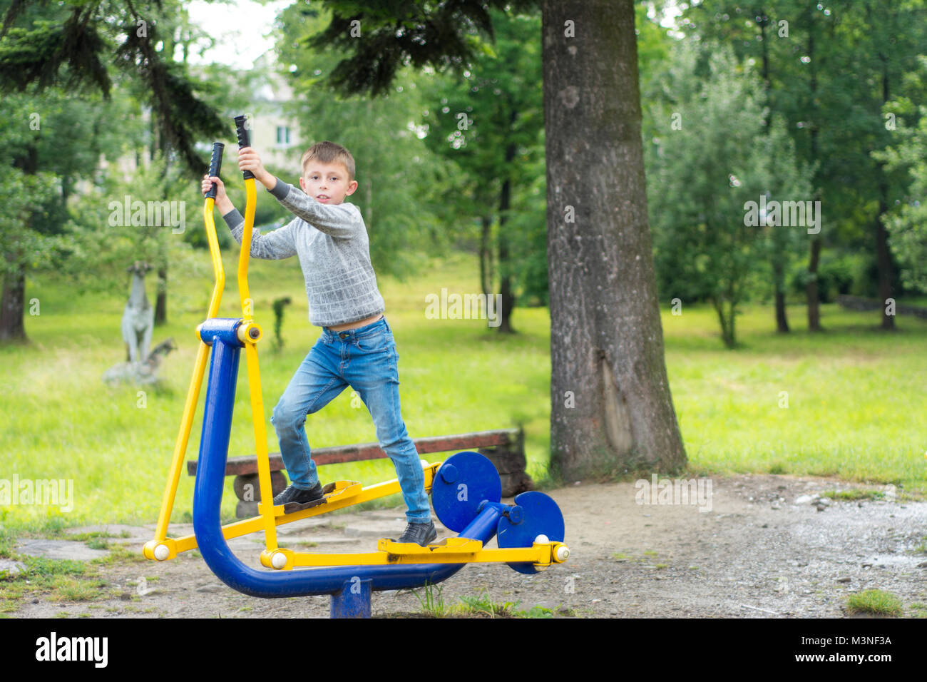 A beautiful little boy running on a track in a park on a sports ground ...