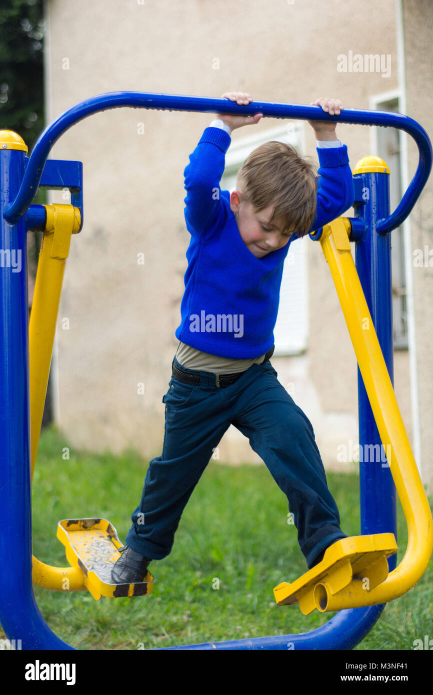 A beautiful little boy running on a track in a park on a sports ground ...