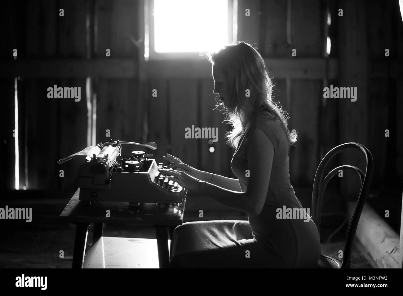 A girl prints on an old typewriter Stock Photo - Alamy
