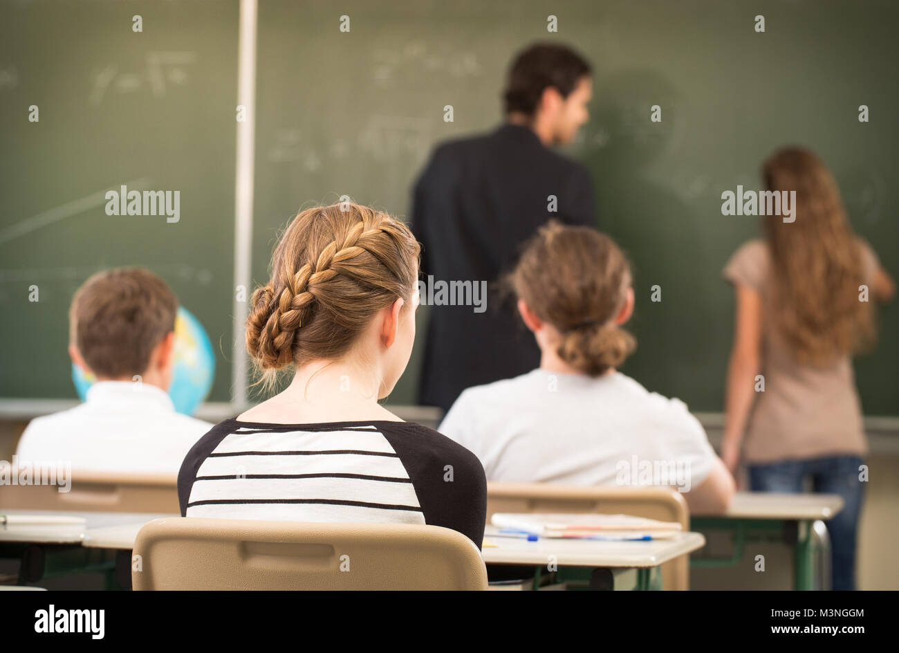 Teacher standing while math lesson in front of a blackboard and educate ...