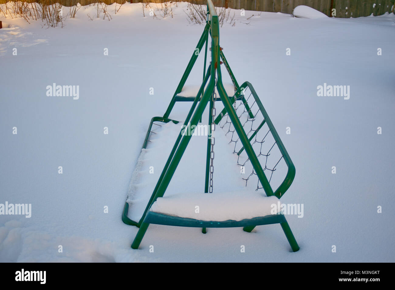 Snow-covered garden swing. wooden garden swing on chains, all in the ...