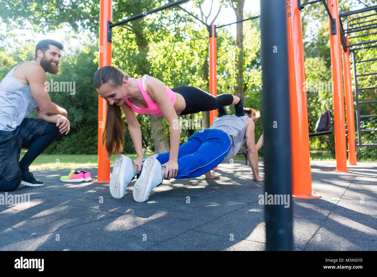 Competitive young woman and her workout partner doing couple push-up ...
