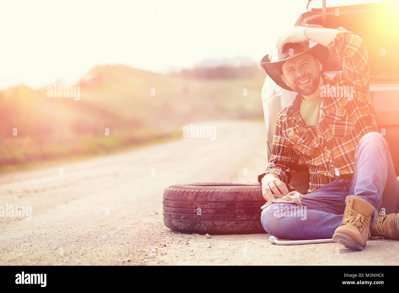 Man is sitting on the road by the car Stock Photo - Alamy