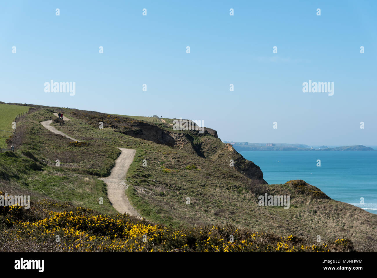 View across hills and cliffs on Cornish coastline with couple in the ...