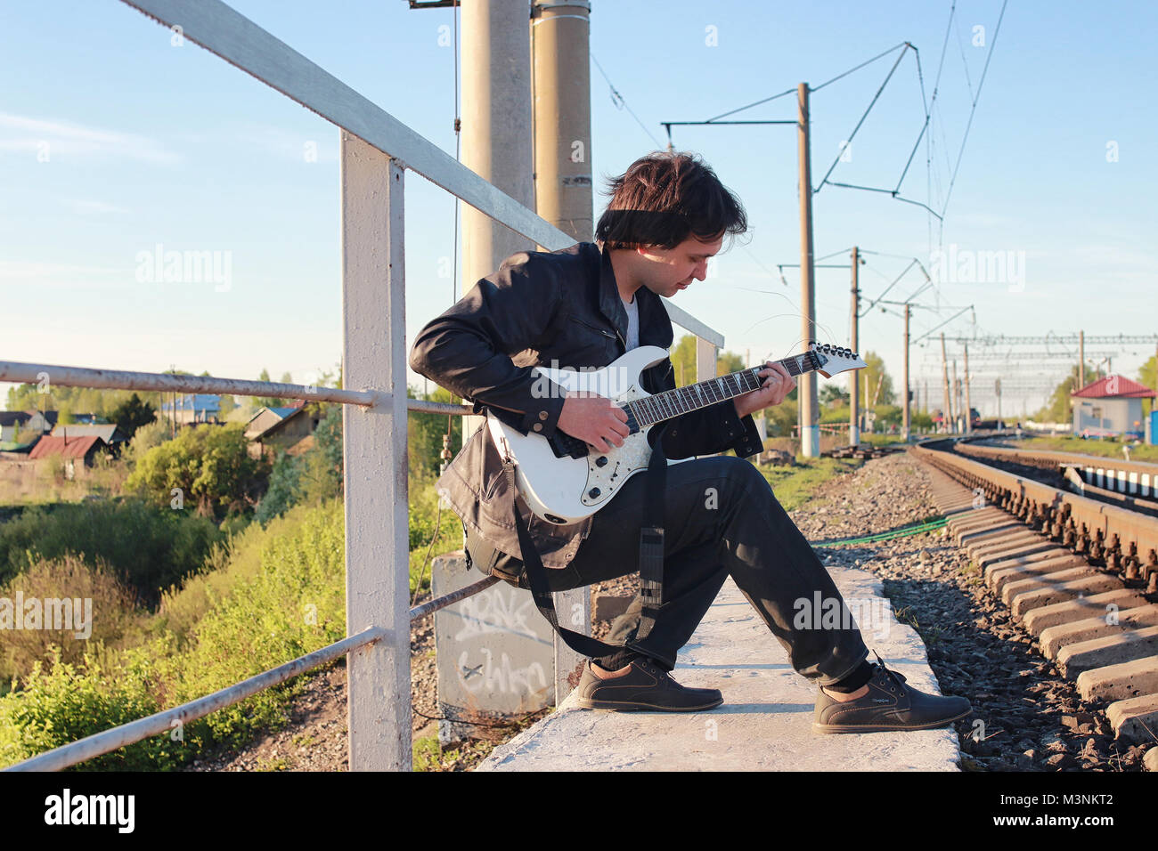 Man with an electric guitar in the industrial landscape outdoors Stock ...