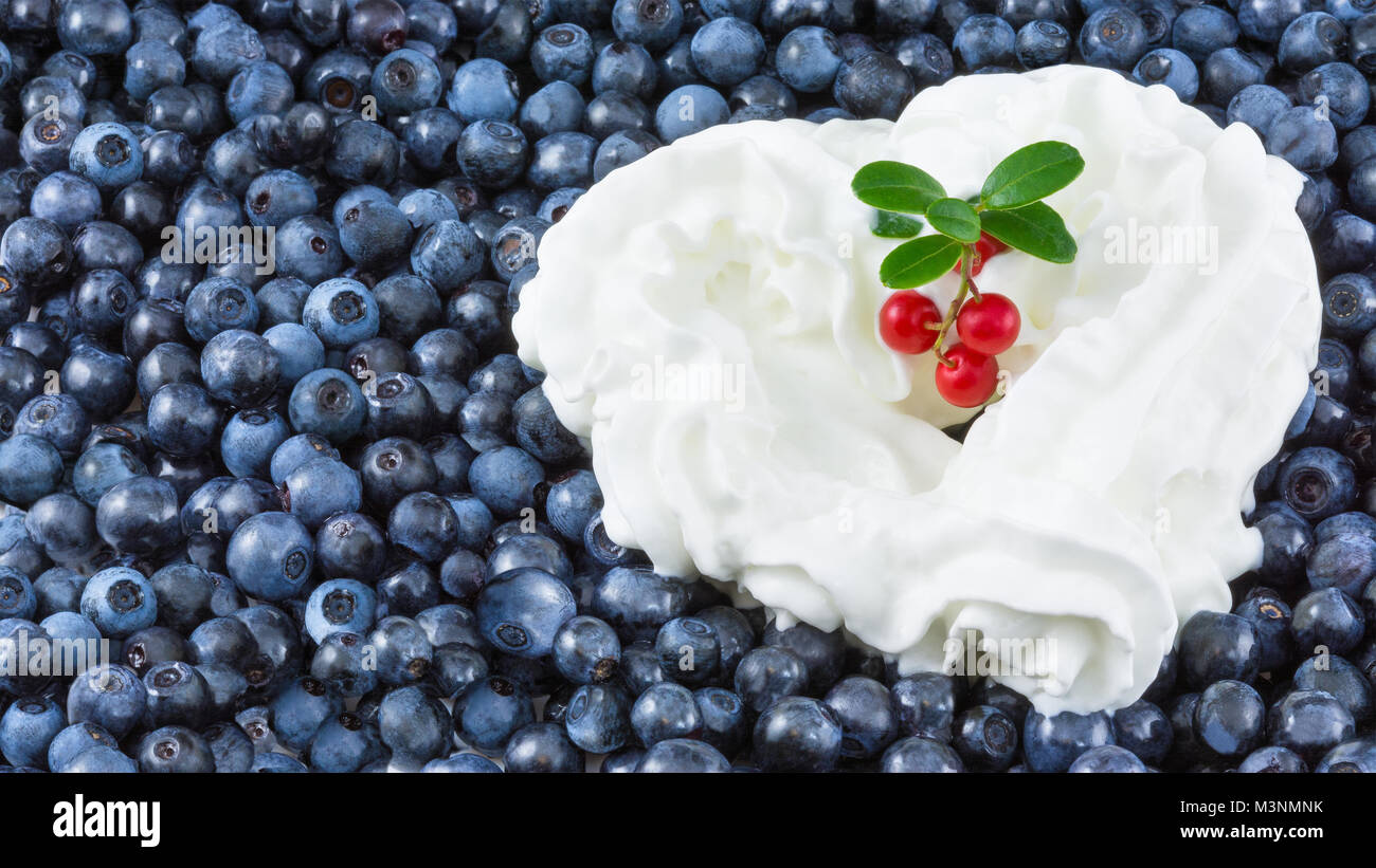 White heart from whipped cream on a blueberry background. Bilberry ...