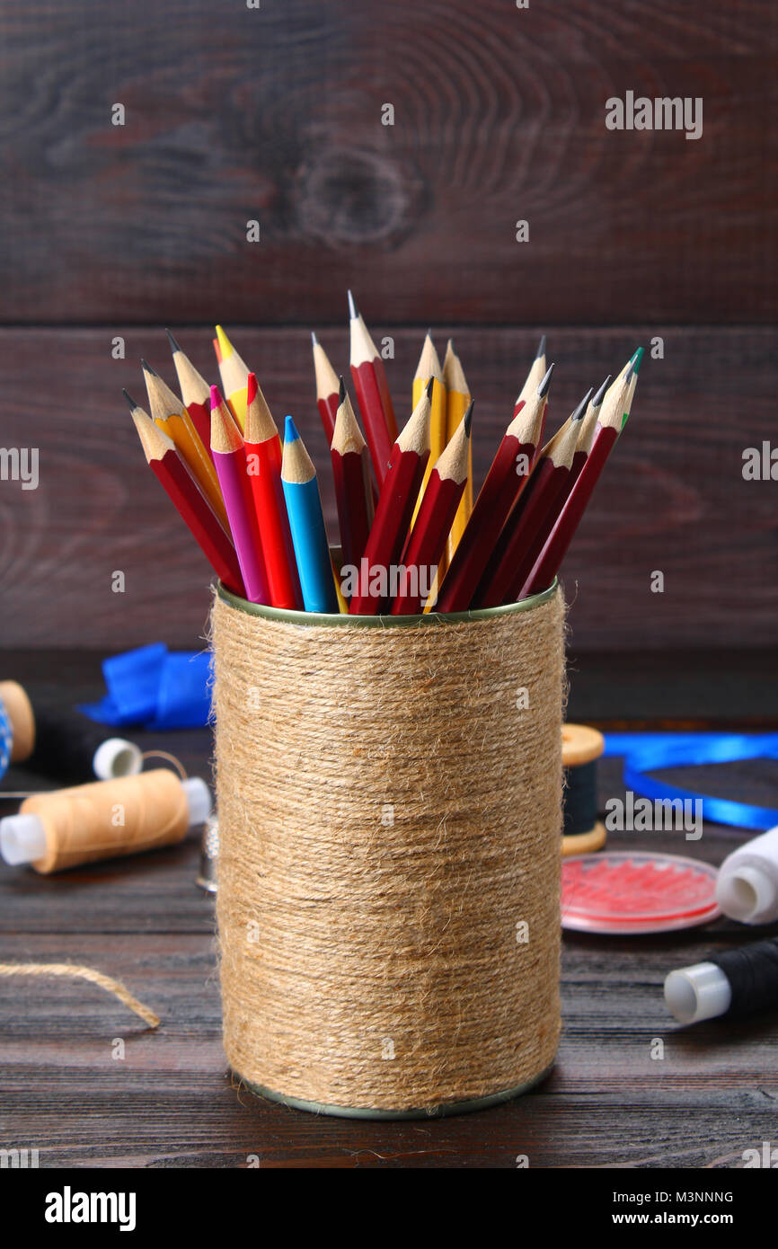 Bank for pencils with hearts wrapped with string on a wooden table ...
