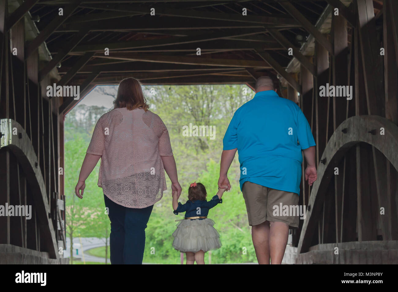 Family Holding Hands While Walking Through a Covered Bridge Stock Photo ...