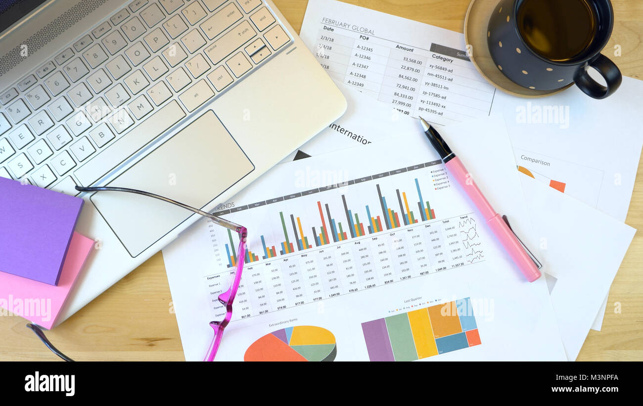 Modern office desk overhead with laptop pc and graphs paperwork ...
