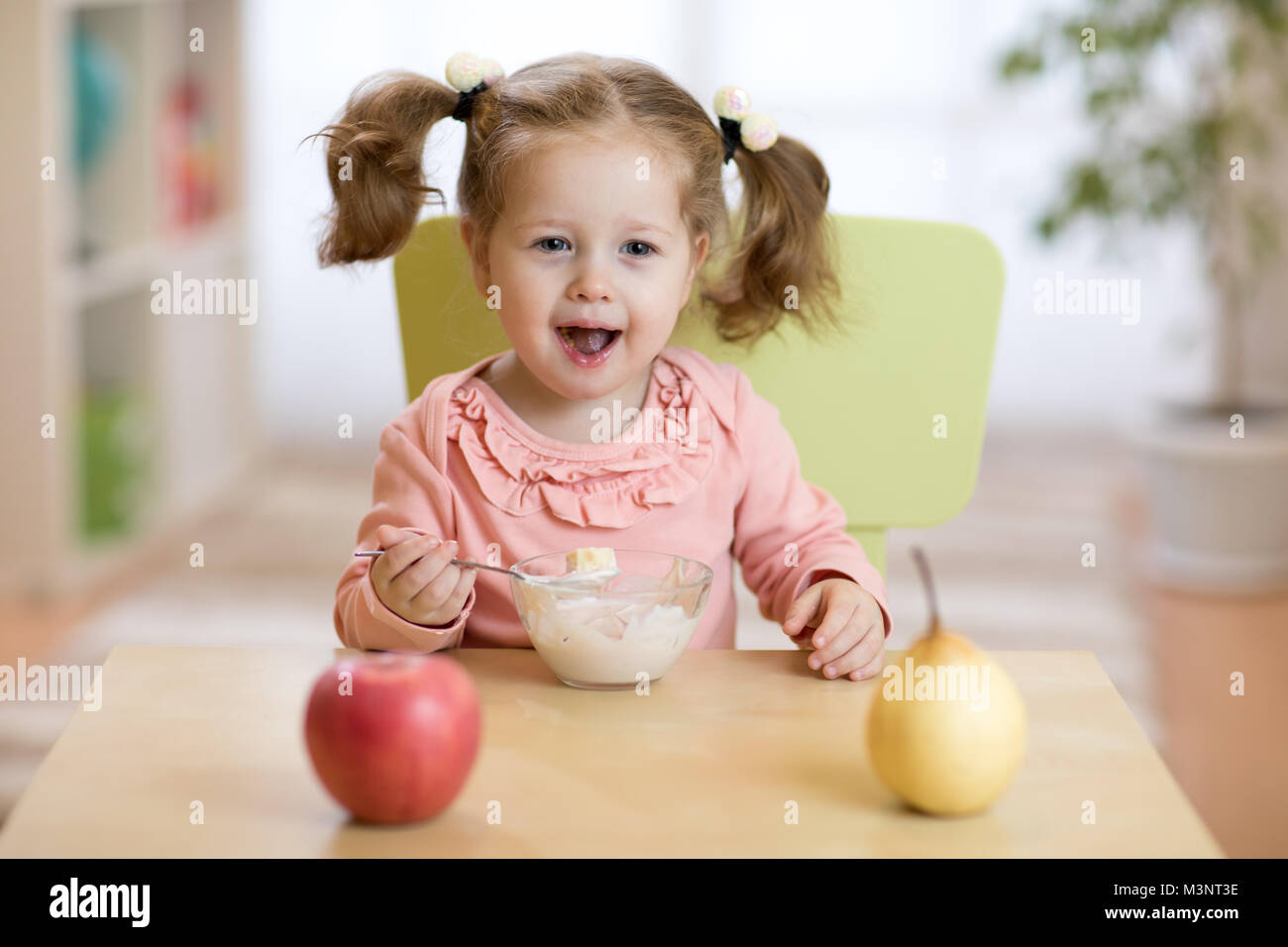 Happy smiling kid eating oatmeal with fruits. The concept of healthy ...