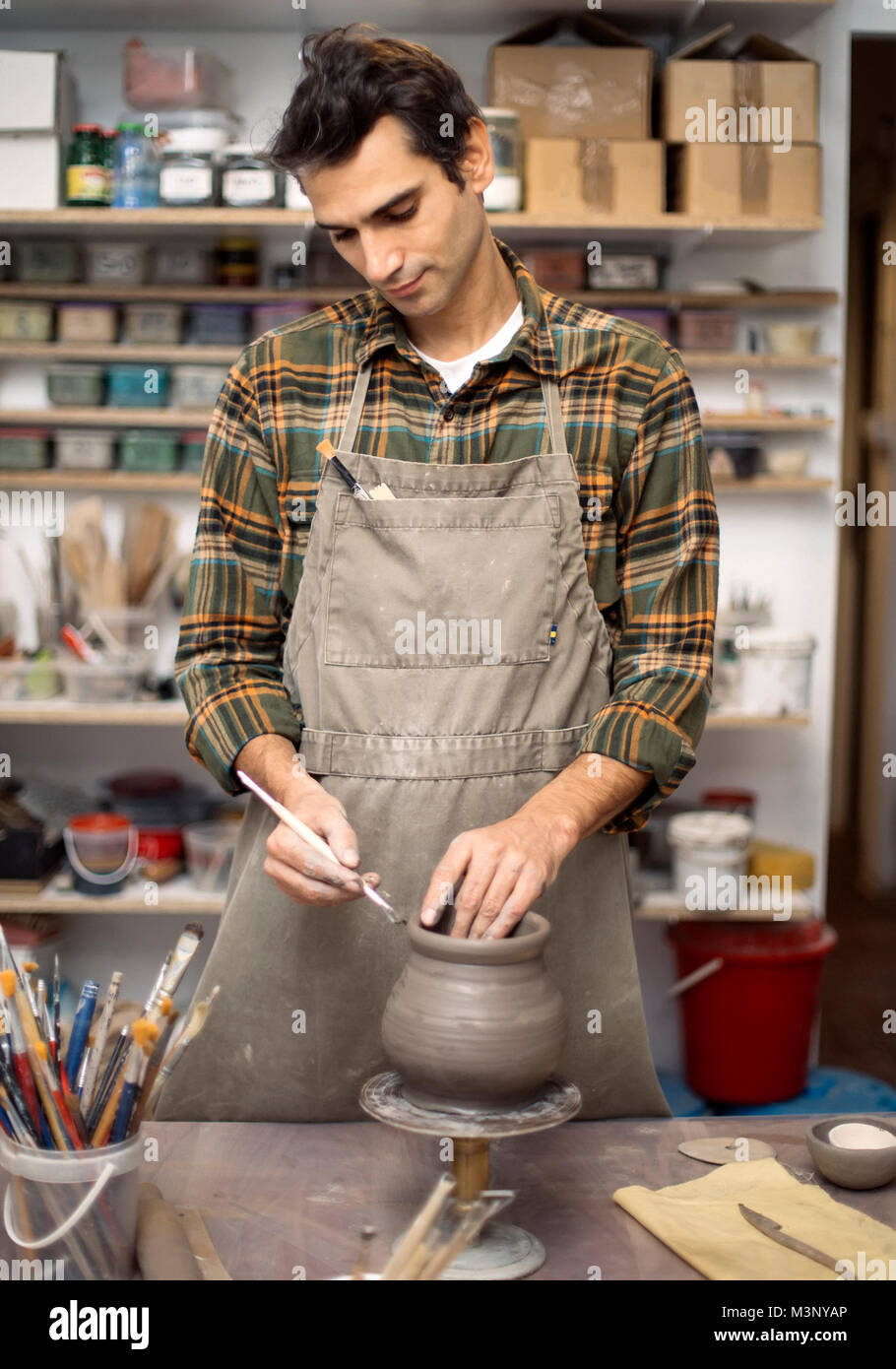 Young man making and decorating pottery in workshop Stock Photo - Alamy