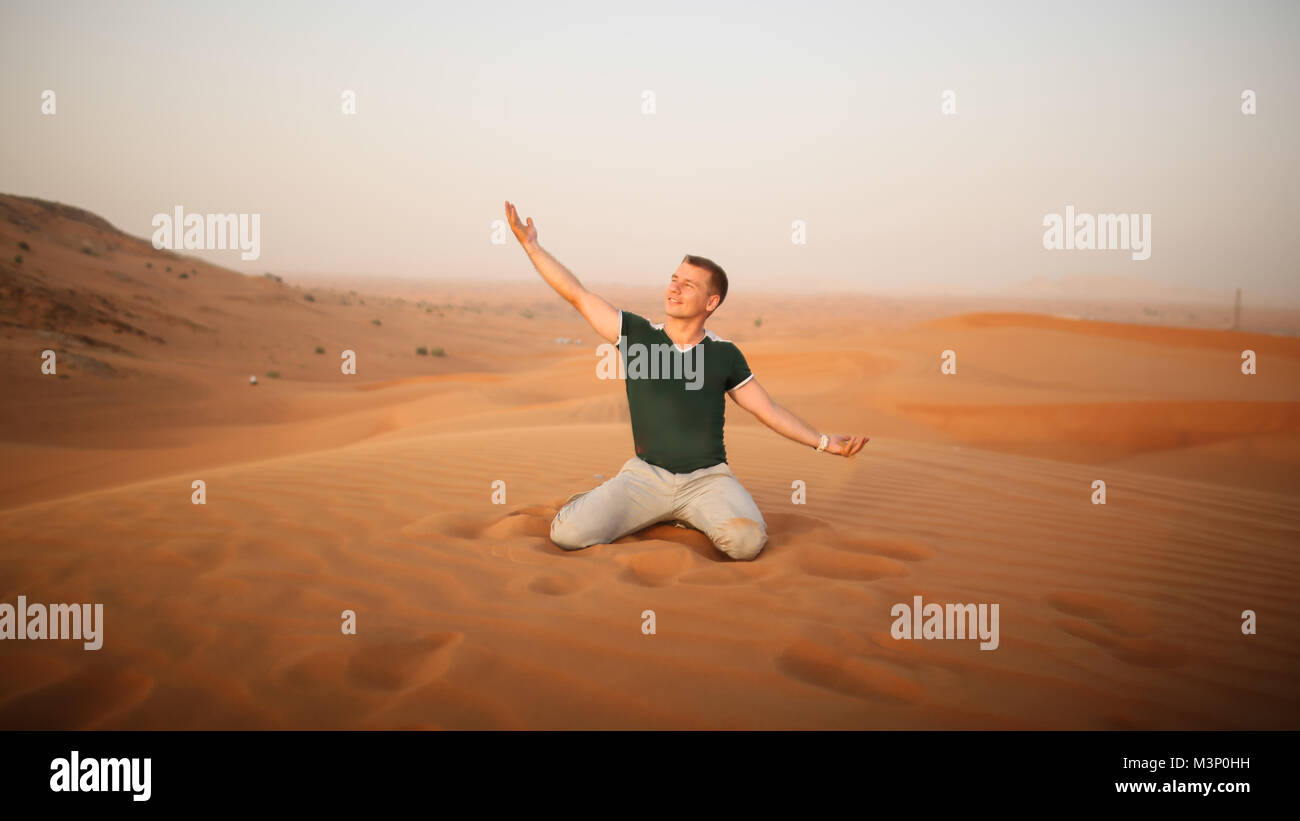 The guy throws sand over himself in the desert. The desert is next to ...