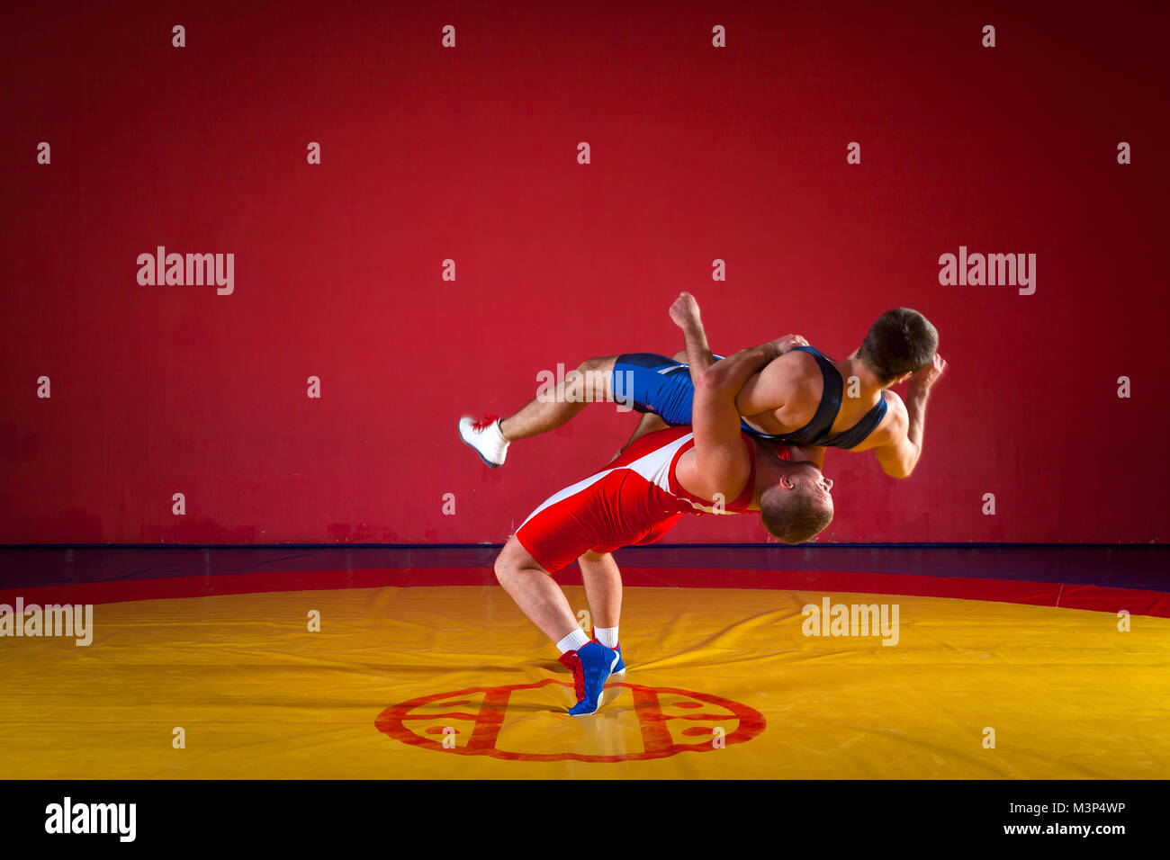 Two greco-roman wrestlers in red and blue uniform making a suplex ...