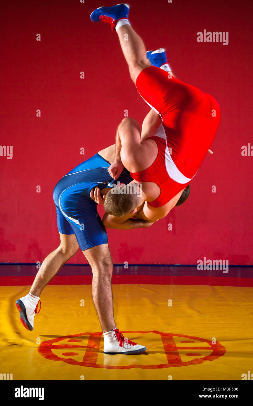 Two greco-roman wrestlers in red and blue uniform making a suplex ...