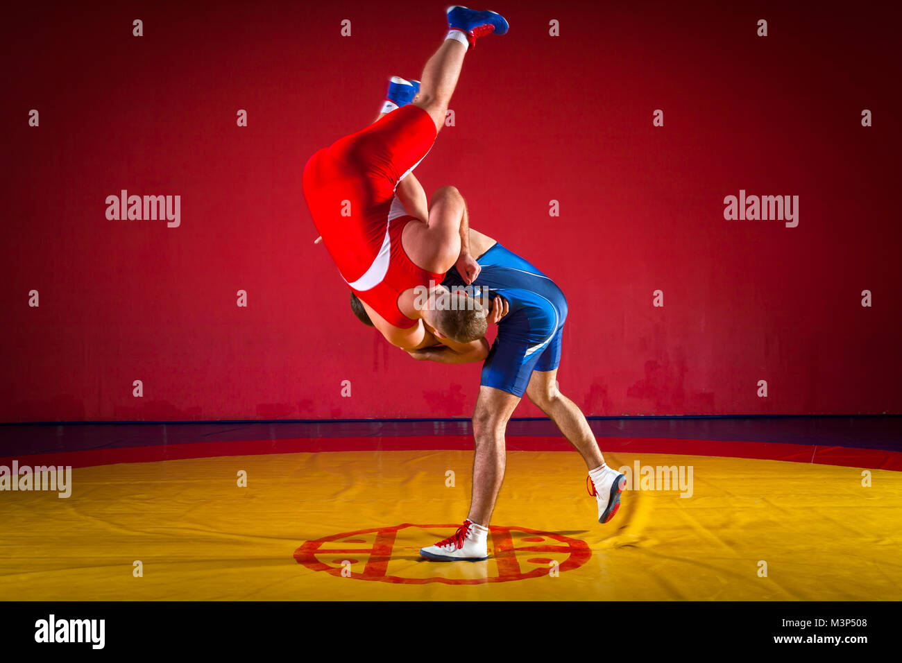Two greco-roman wrestlers in red and blue uniform making a suplex ...