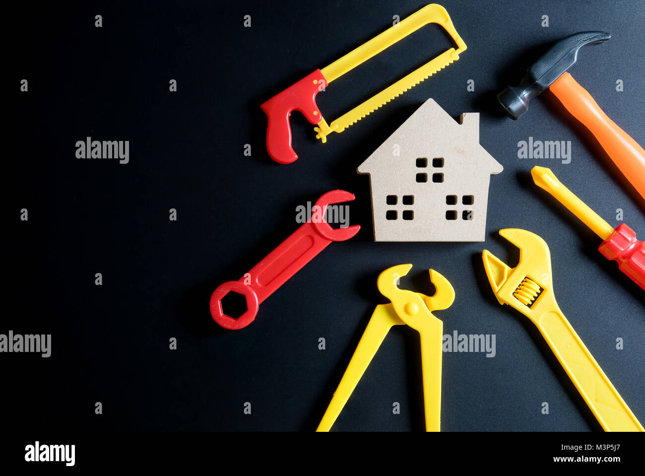 Wooden house toy and construction tools toy on black background with ...