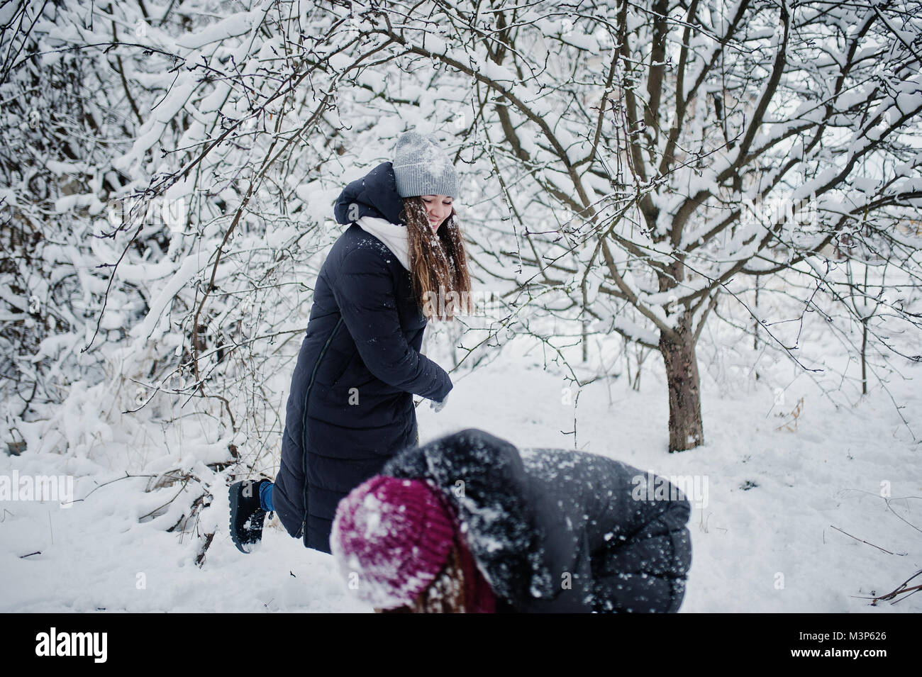 Two funny girls friends having fun at winter snowy day near snow ...