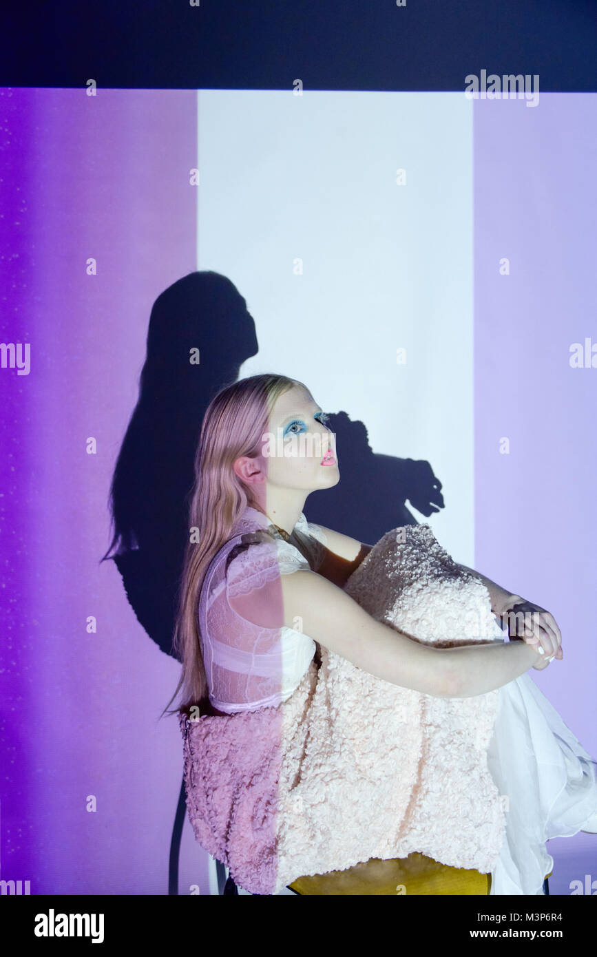 A beautiful girl with bright make up and long blond hair has light and ...