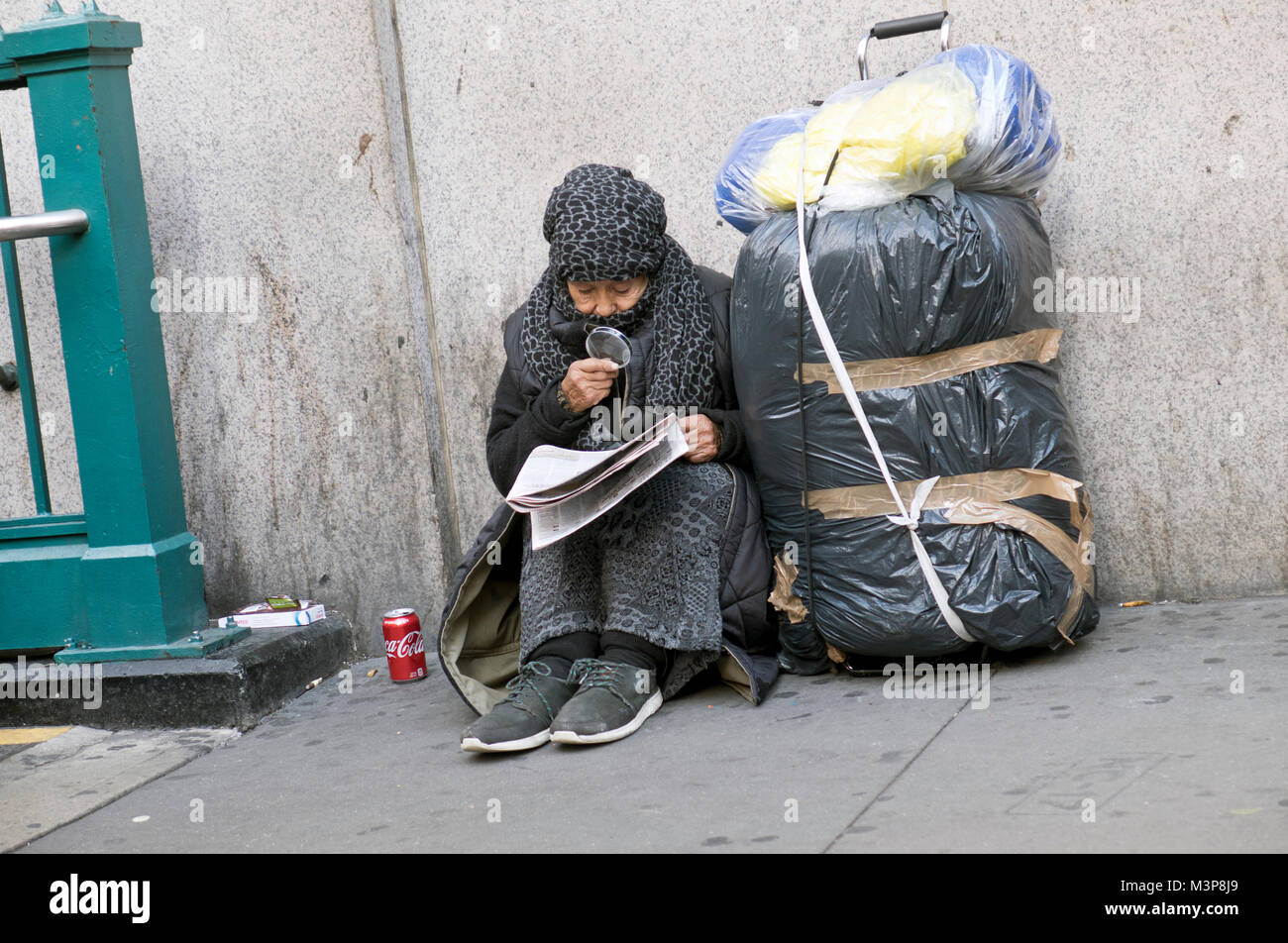 Homeless woman reading a book with a magnifying glass on Manhattan ...