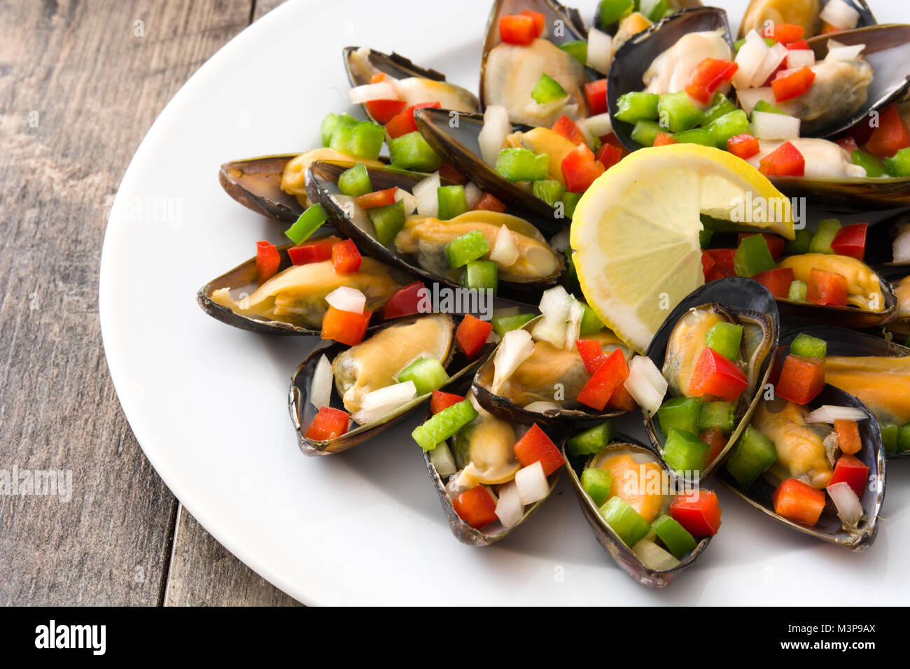 Steamed mussels with peppers and onion on wooden table Stock Photo - Alamy