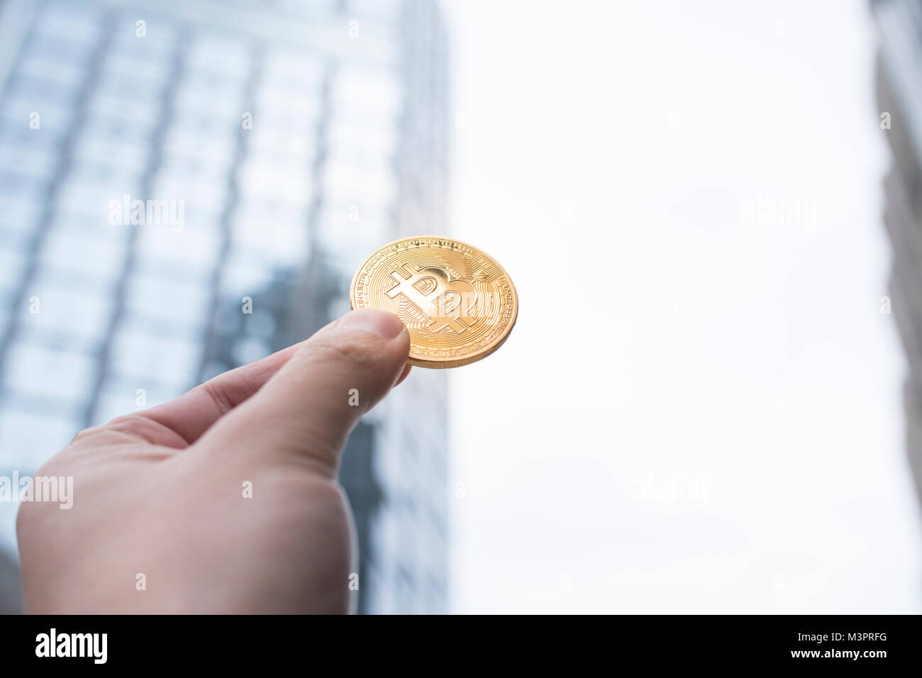 hand holding one bitcoin with the city high office building background ...