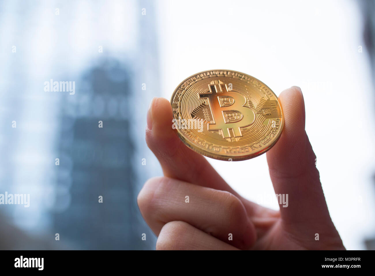 hand holding one bitcoin with the city high office building background ...